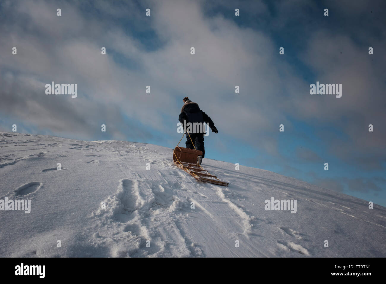 Low angle view of man pulling sled while walking on snow covered ...