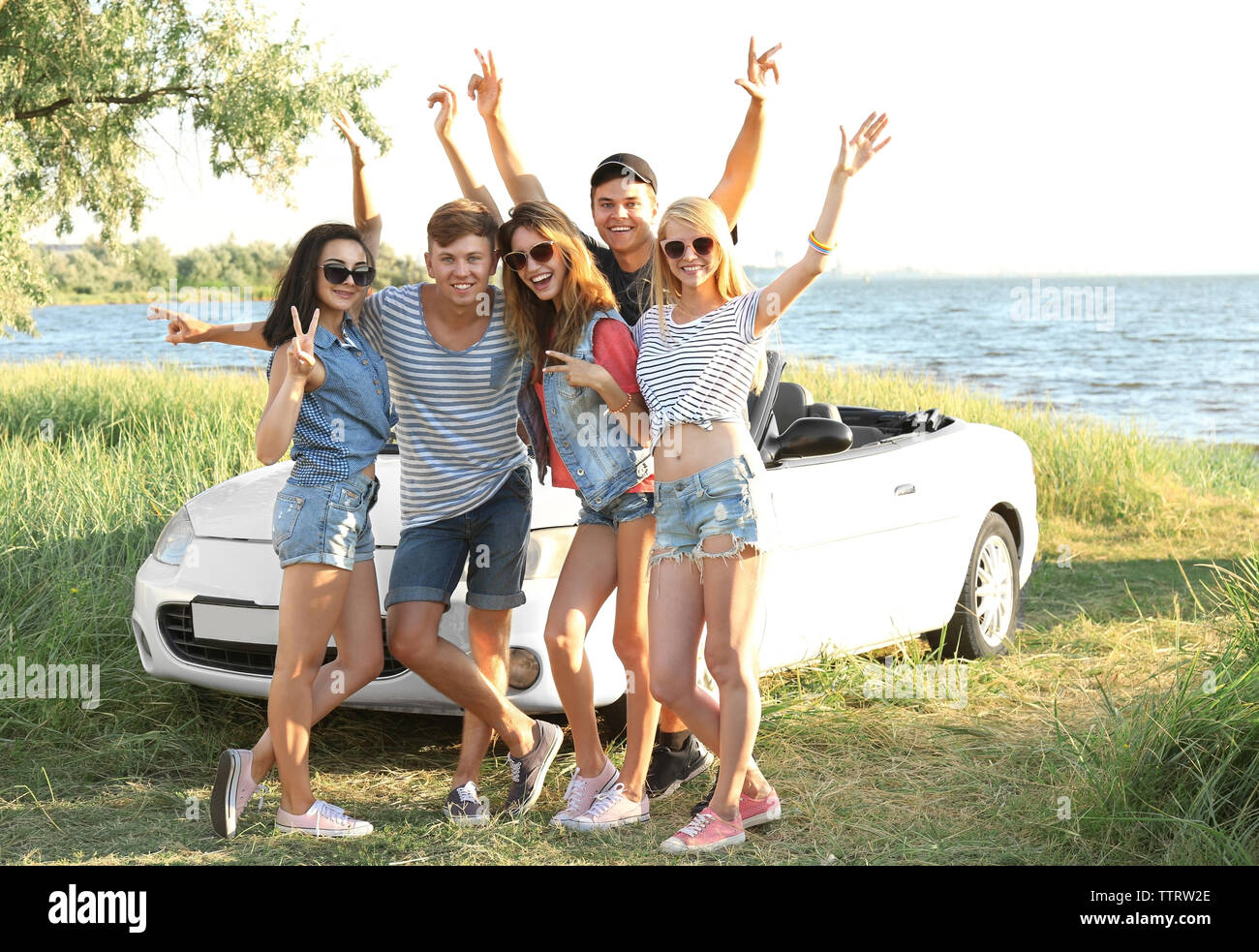 Happy friends near car Stock Photo - Alamy