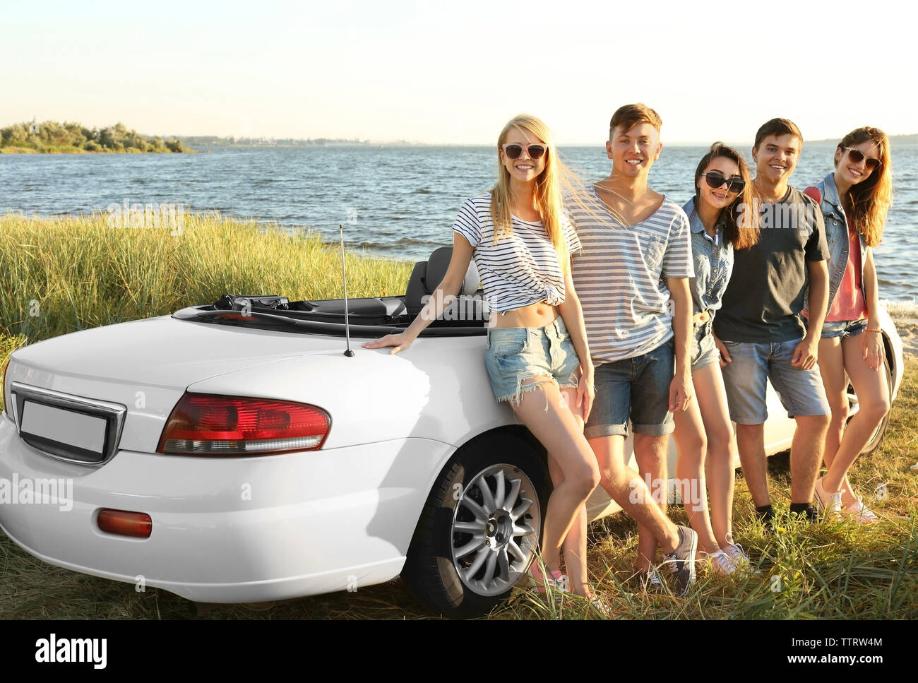 Happy friends near car Stock Photo - Alamy