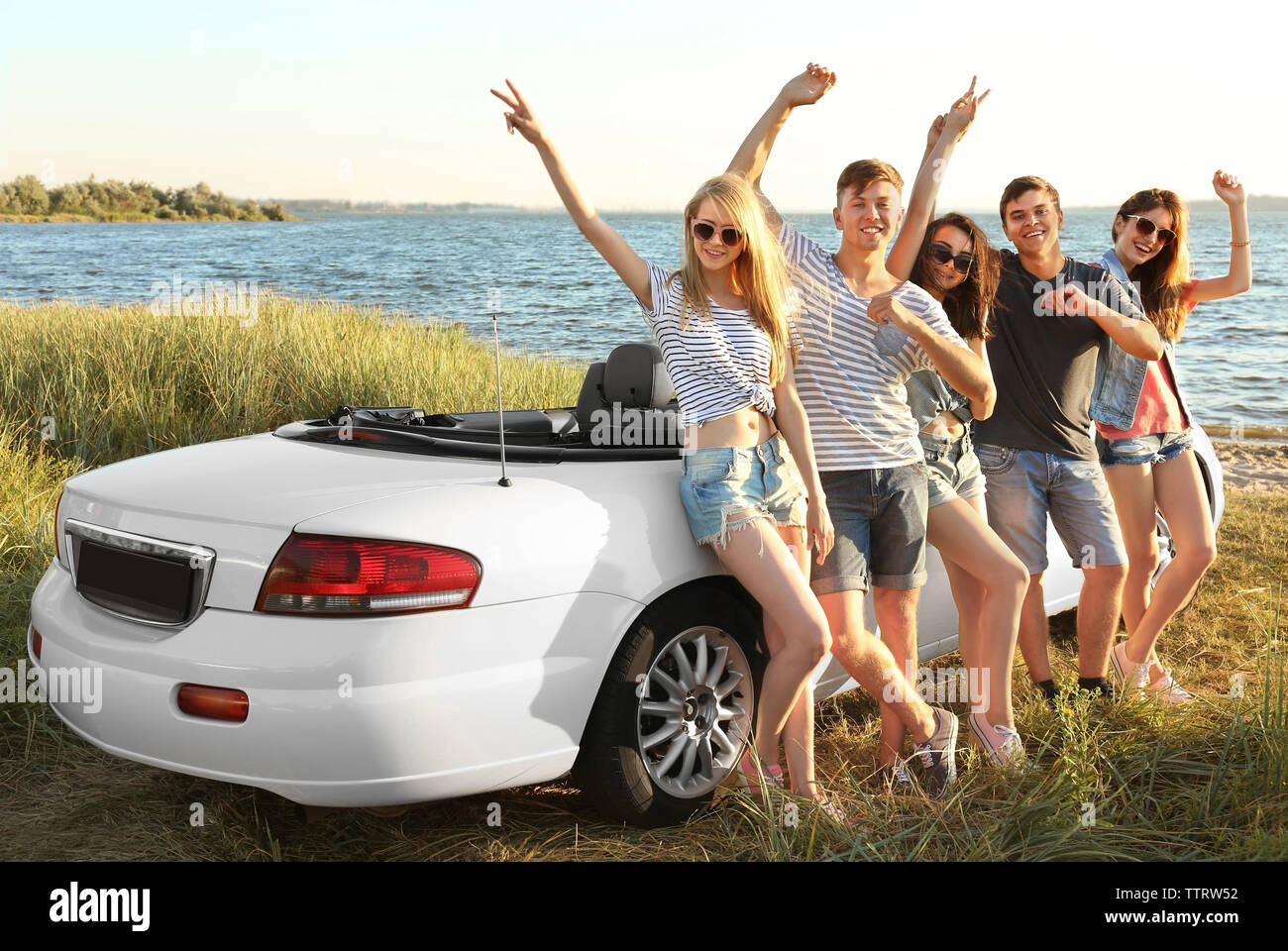 Happy friends near car Stock Photo - Alamy