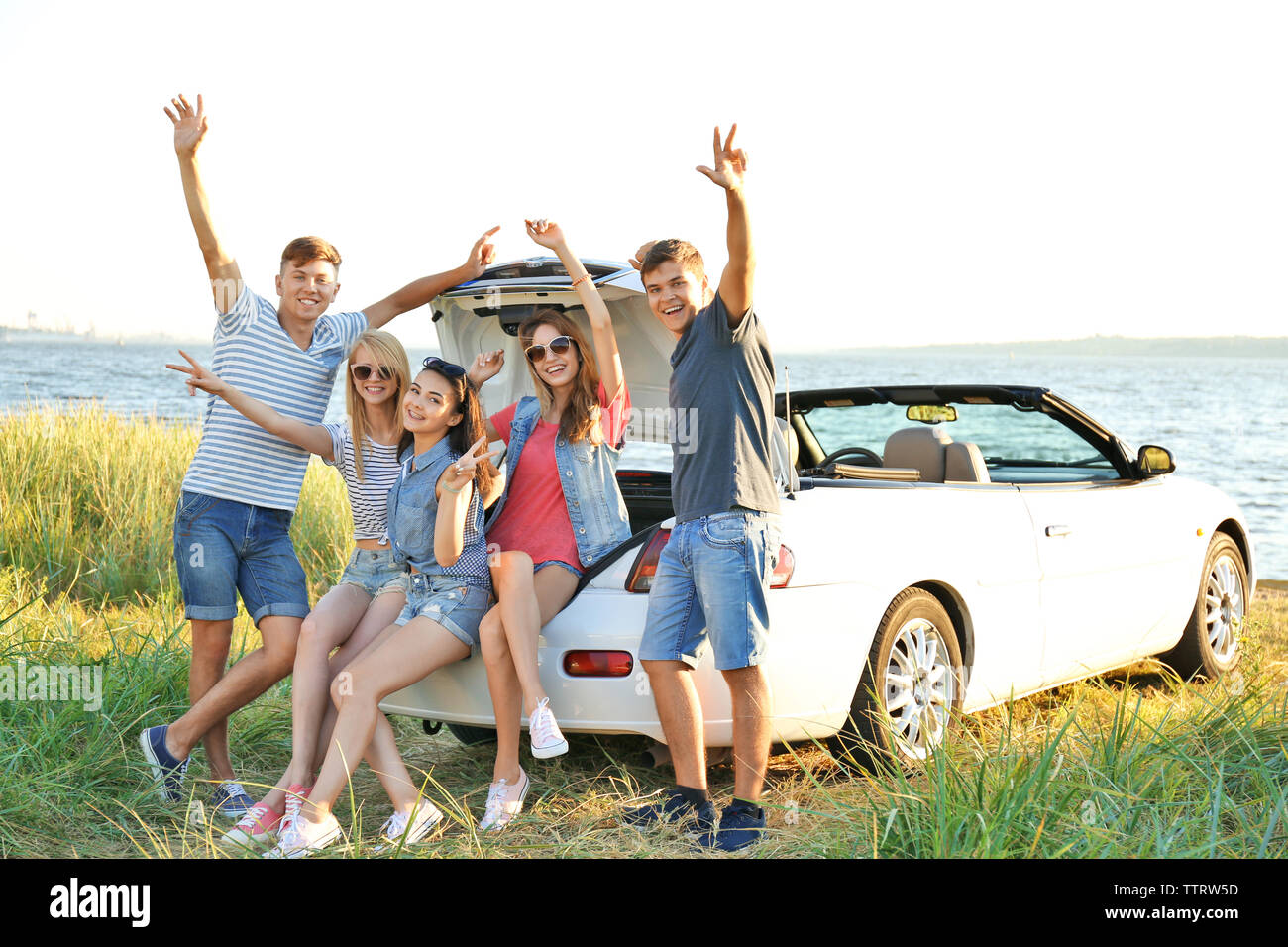 Happy friends near car Stock Photo - Alamy