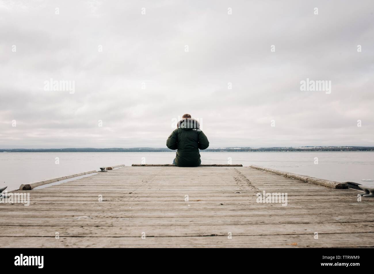 man sitting on the end of a pier jetty looking out to the water Stock ...
