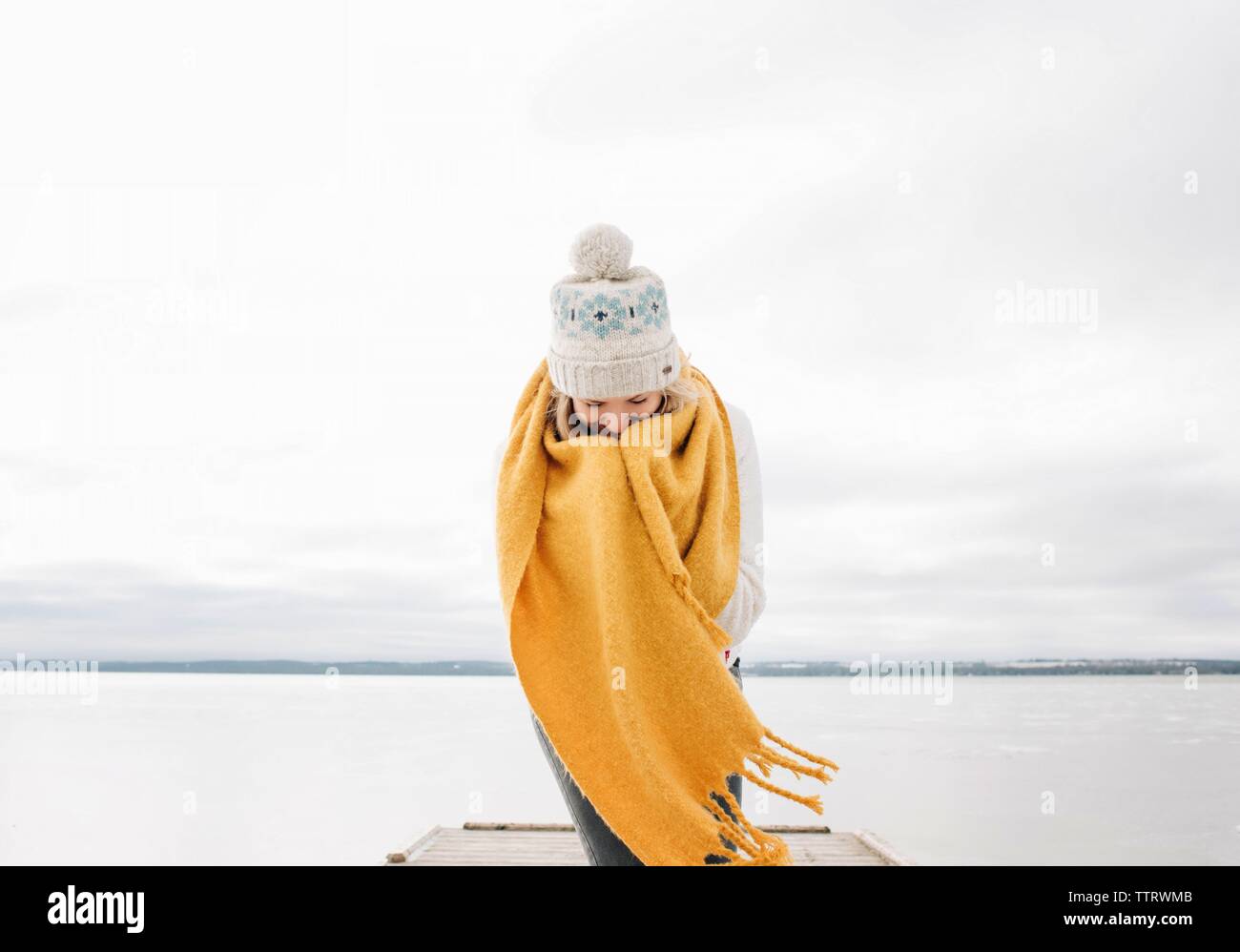 woman wrapped up in scarf smiling keeping warm at the beach Stock Photo ...