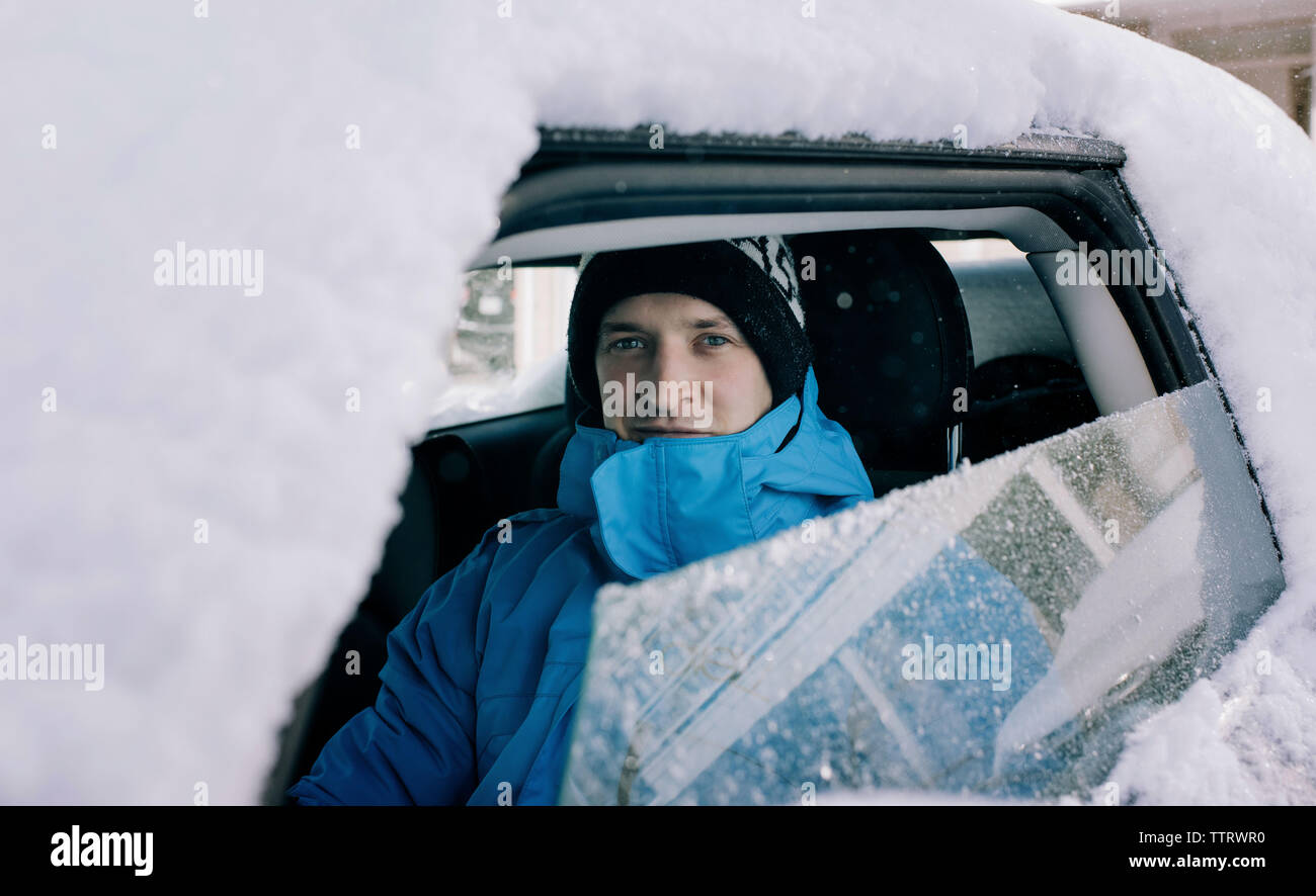 man looking out of car window covered in snow wearing winter clothes ...