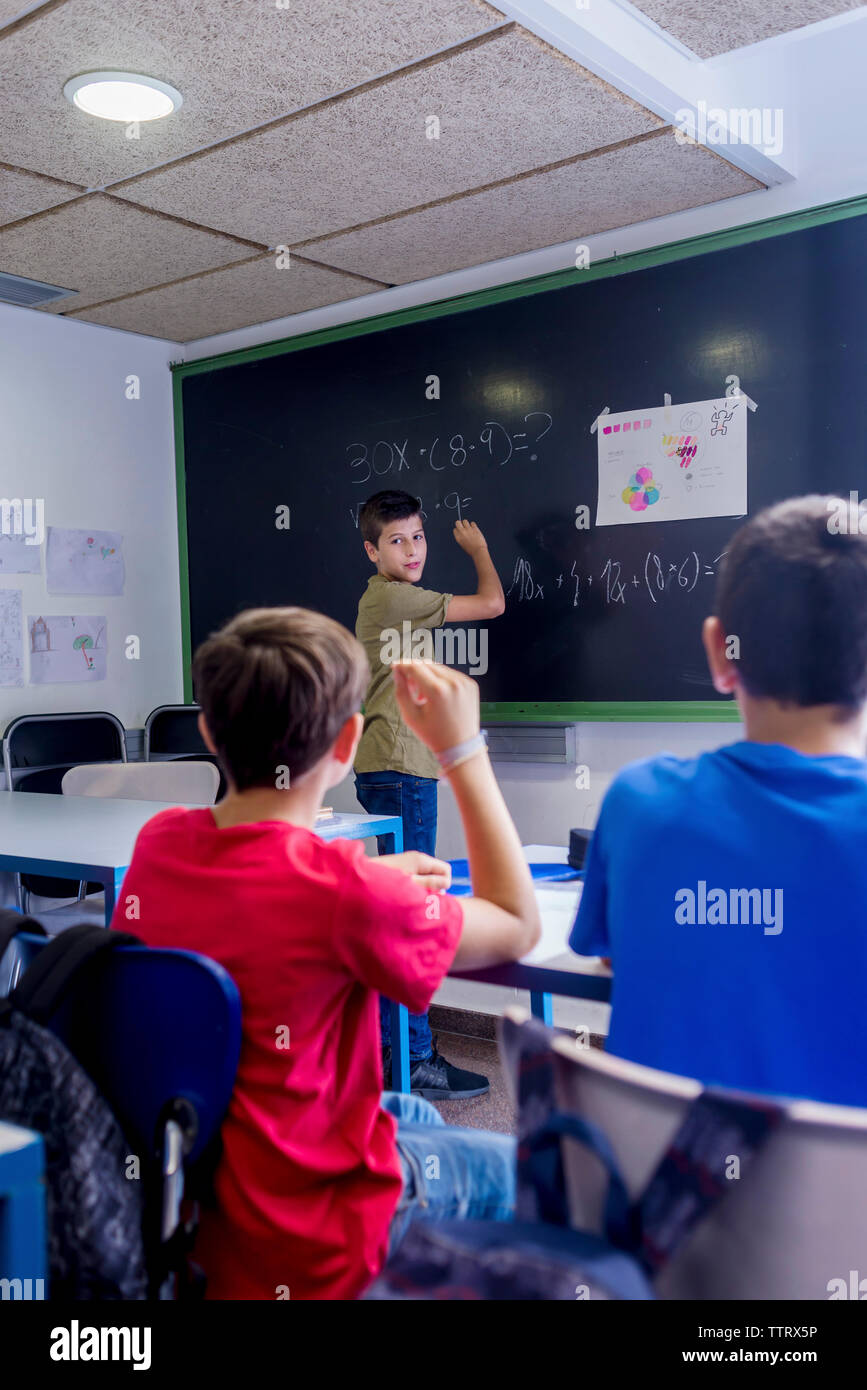 Boy explaining mathematics to friends in classroom Stock Photo - Alamy