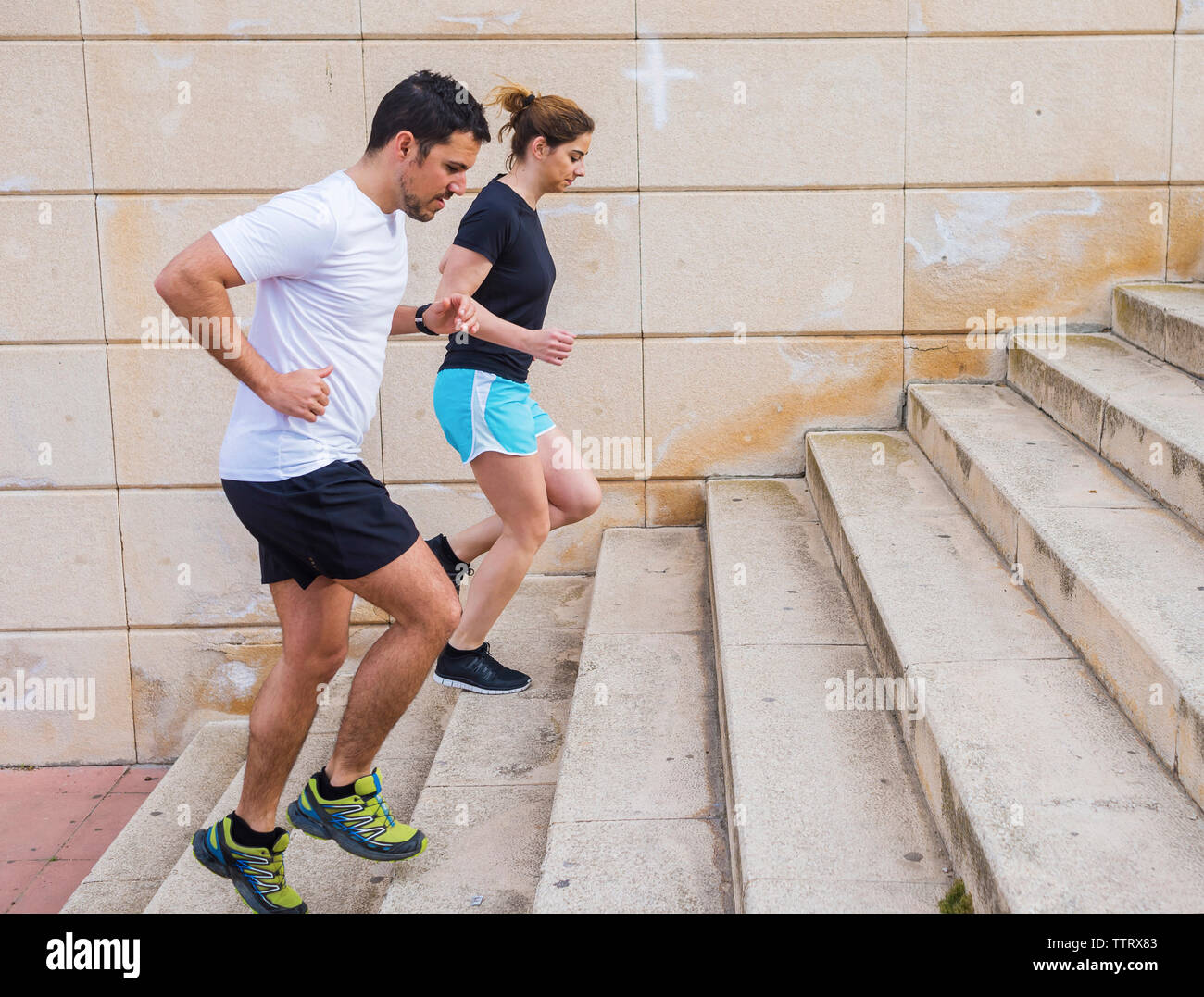 Side view of couple running on steps at park in city Stock Photo - Alamy