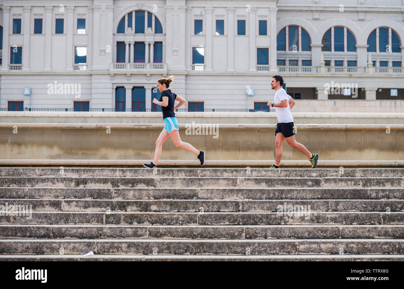 Side view of couple running on steps against building in city Stock ...