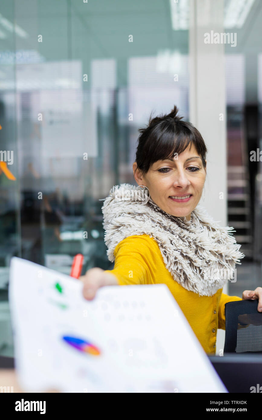Front view of a business woman giving you a chart document at office ...
