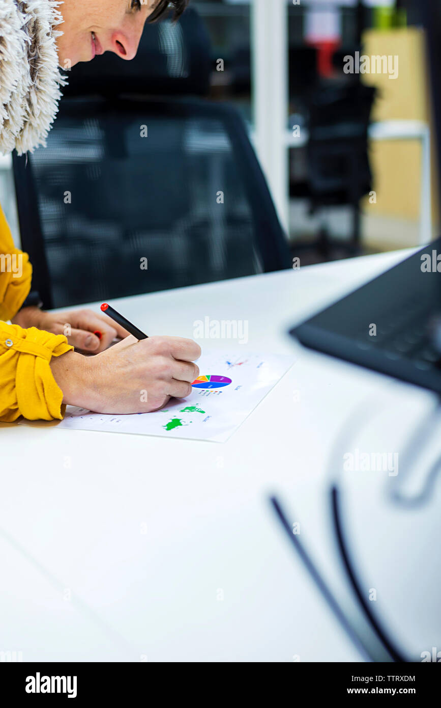 Side view of businesswoman writting on chart on the office table Stock ...