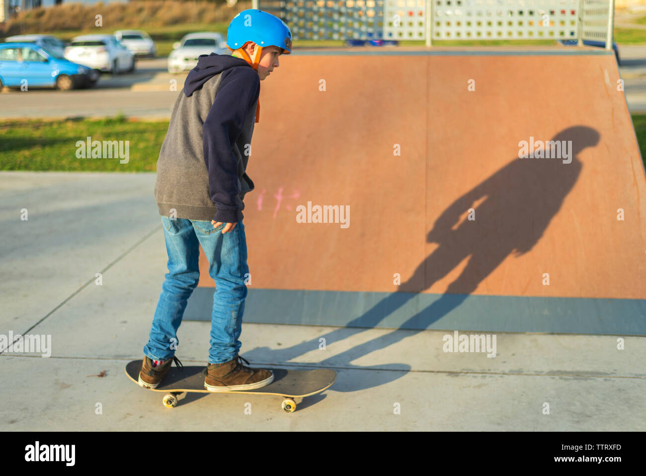 Side view of young skater with blue helmet riding next to a skateramp ...