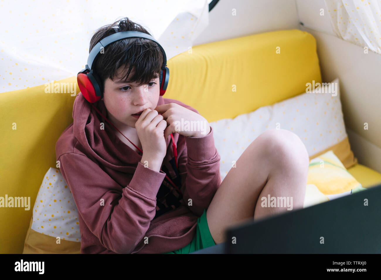 Above view of teen sitting on sofa with headphones looking laptop Stock ...