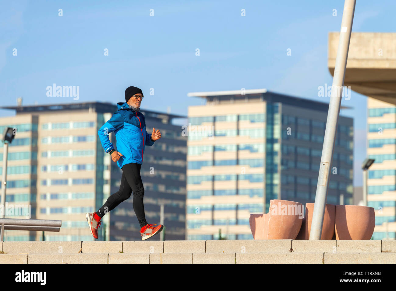 Side view of senior man jogging against city skyline in the morning ...
