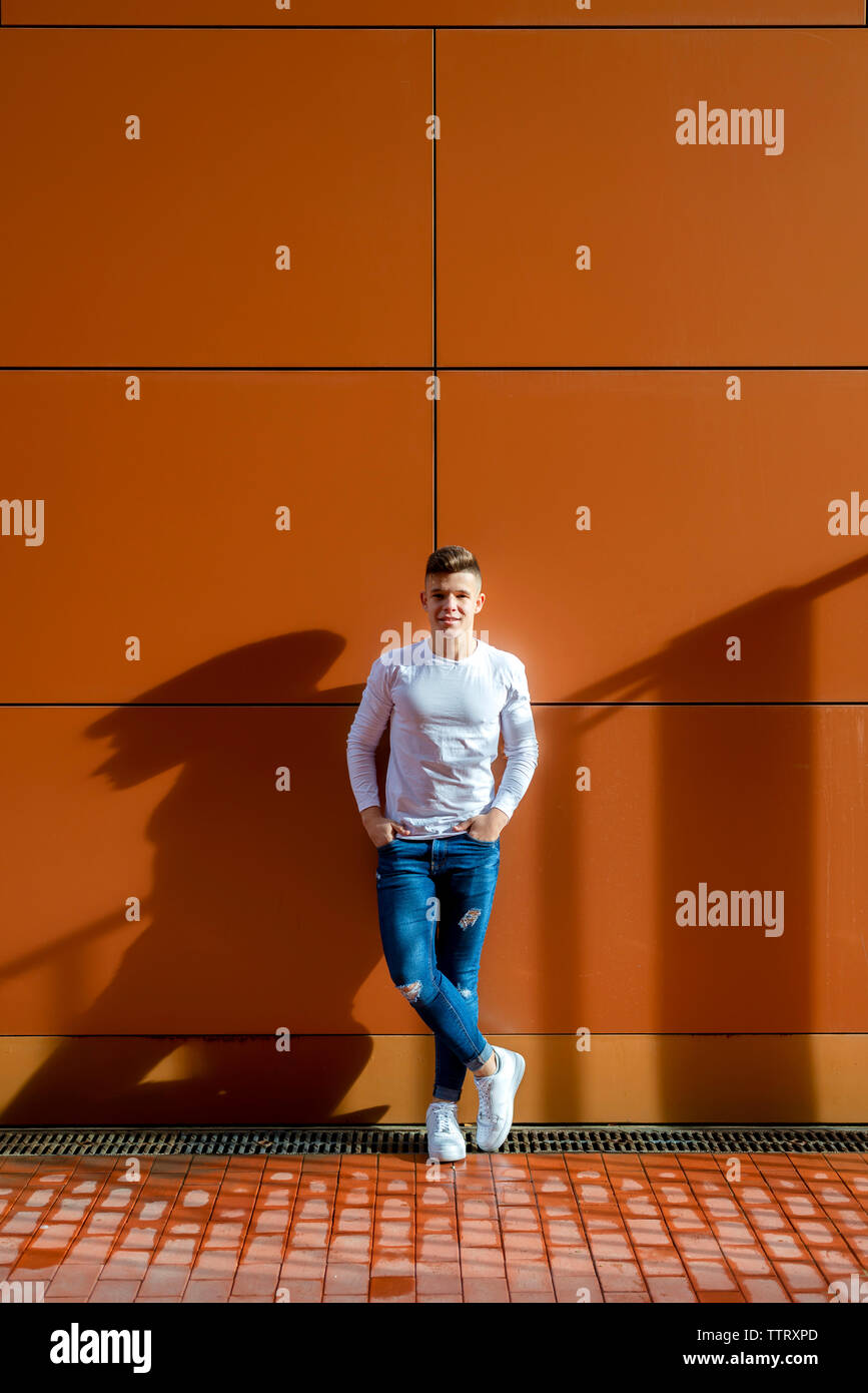 Front view young man leaning on a wall while looking camera Stock Photo ...