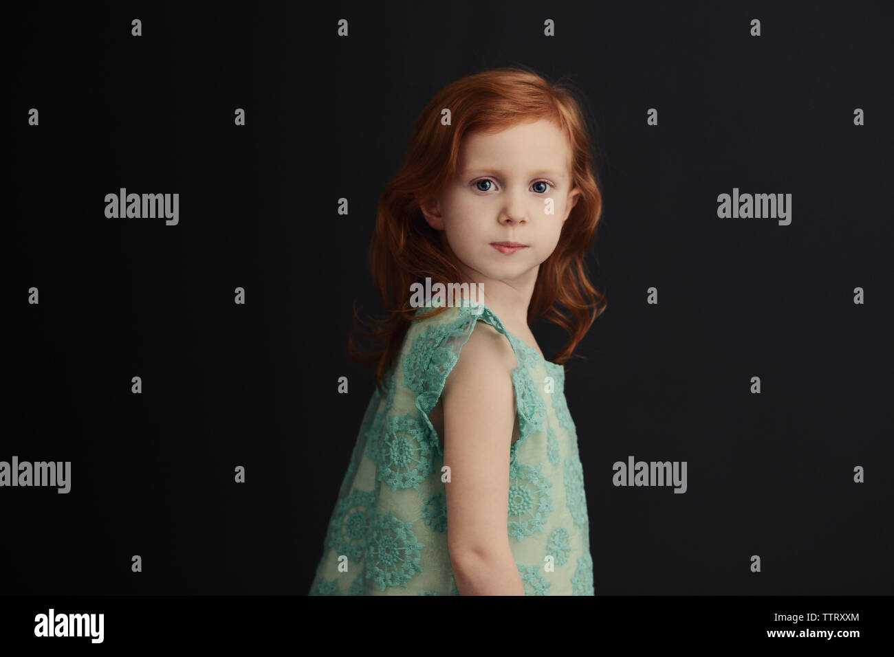 Portrait of girl standing against black background Stock Photo - Alamy