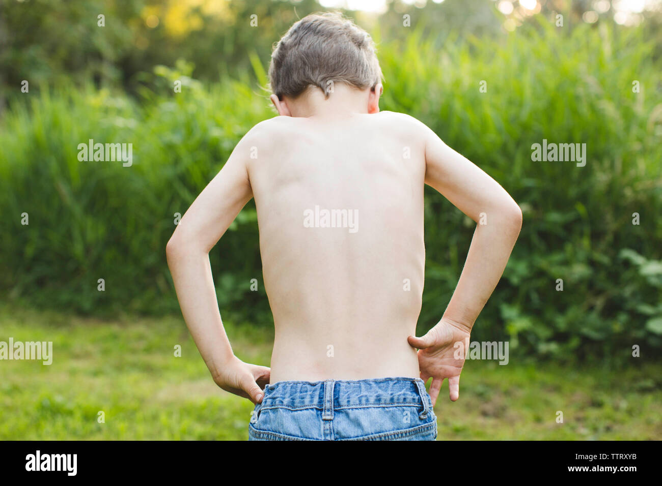 Rear view of shirtless boy standing on field in park Stock Photo - Alamy