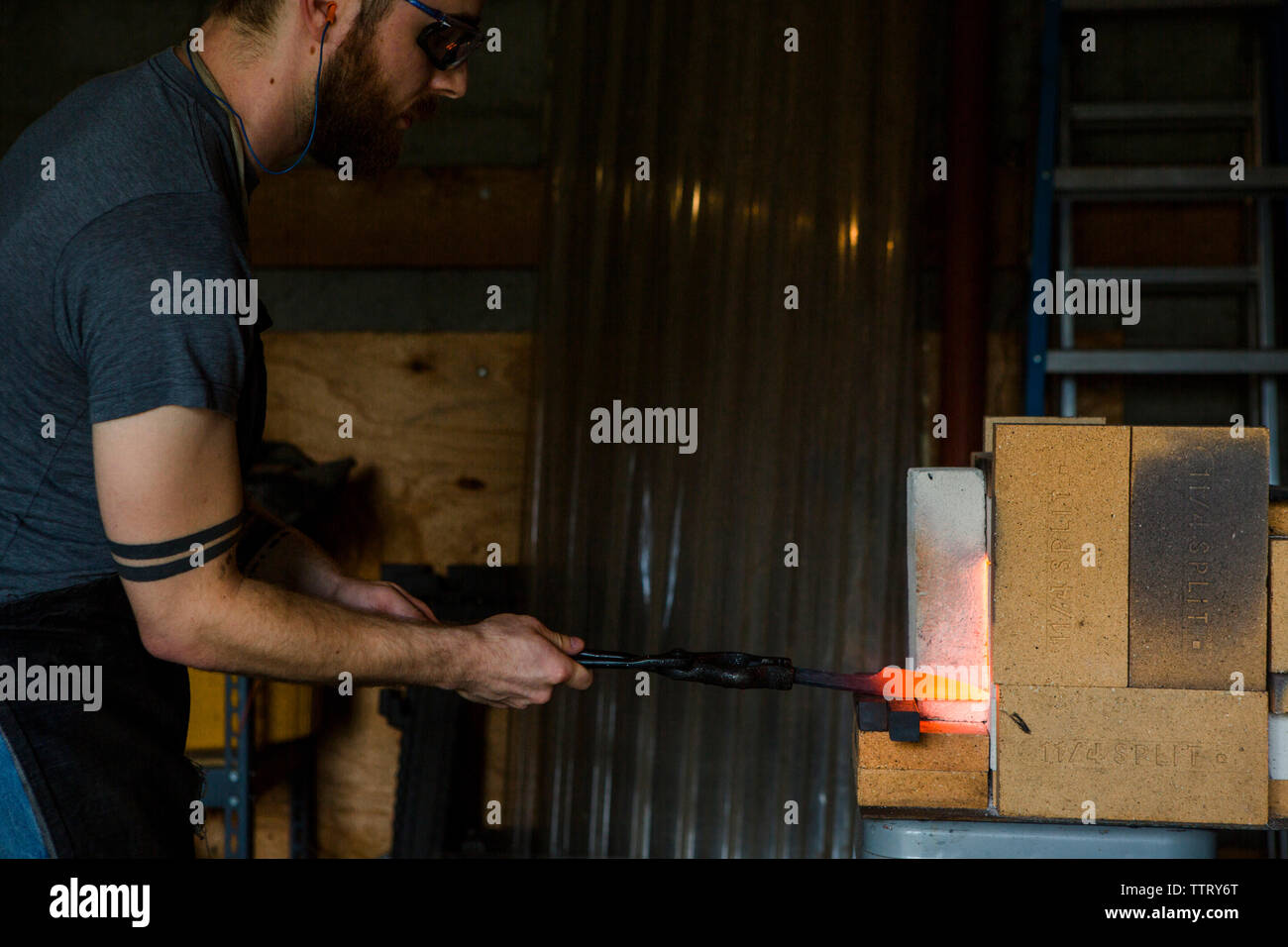 Side view of blacksmith forging metal on furnace in workshop Stock ...