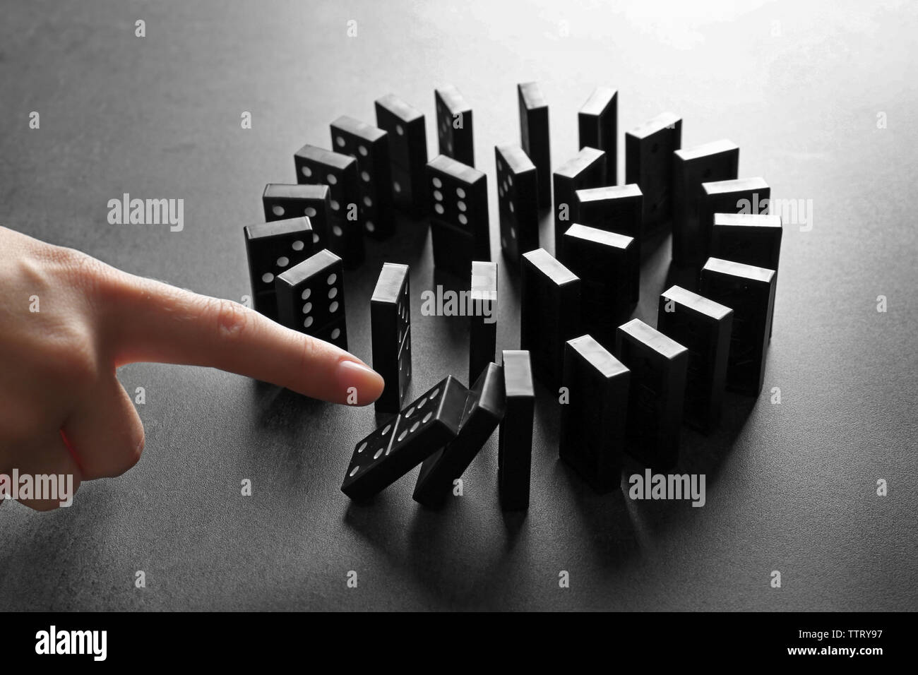 Female hand pushing dominoes on grey background Stock Photo - Alamy