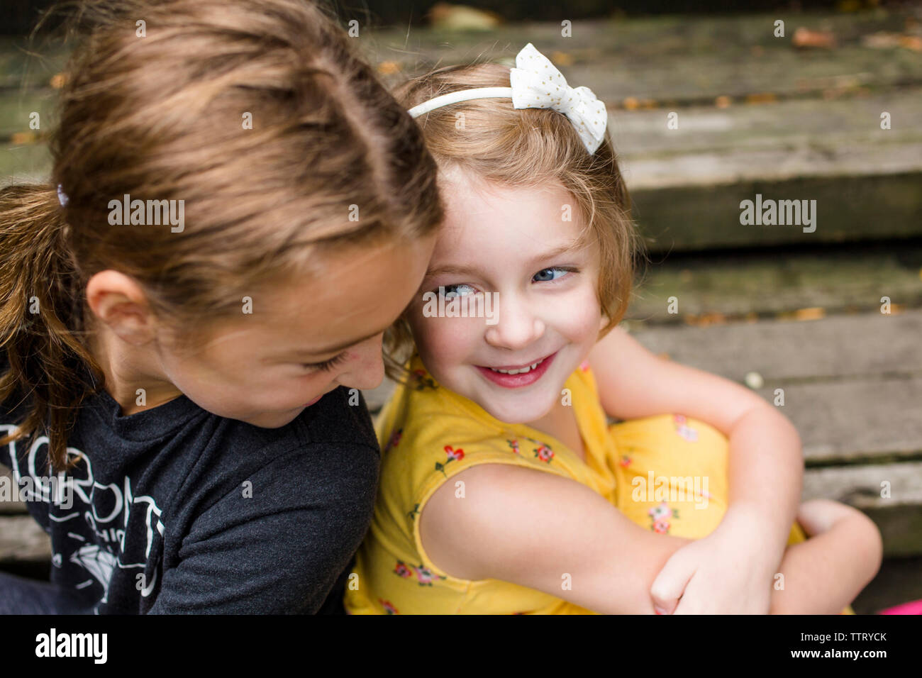 High angle view of smiling cute sisters looking at each other while ...