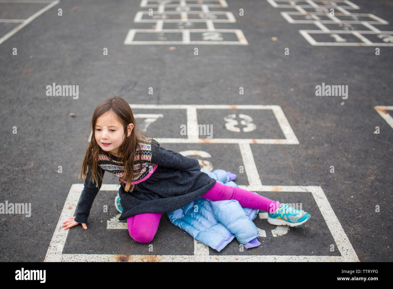 Small girl stretches out on a school playground hopscotch board Stock ...