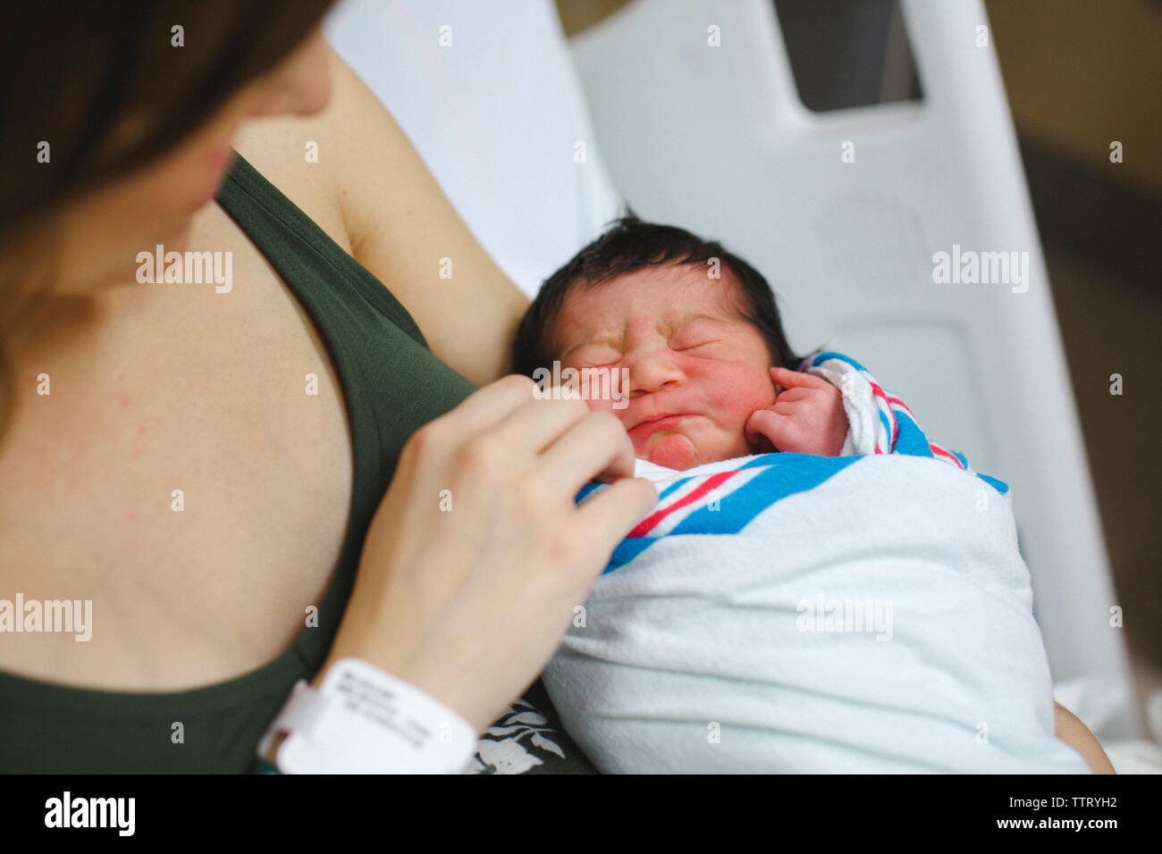 a cute newborn baby girl rests cradled in her mother's arms Stock Photo ...