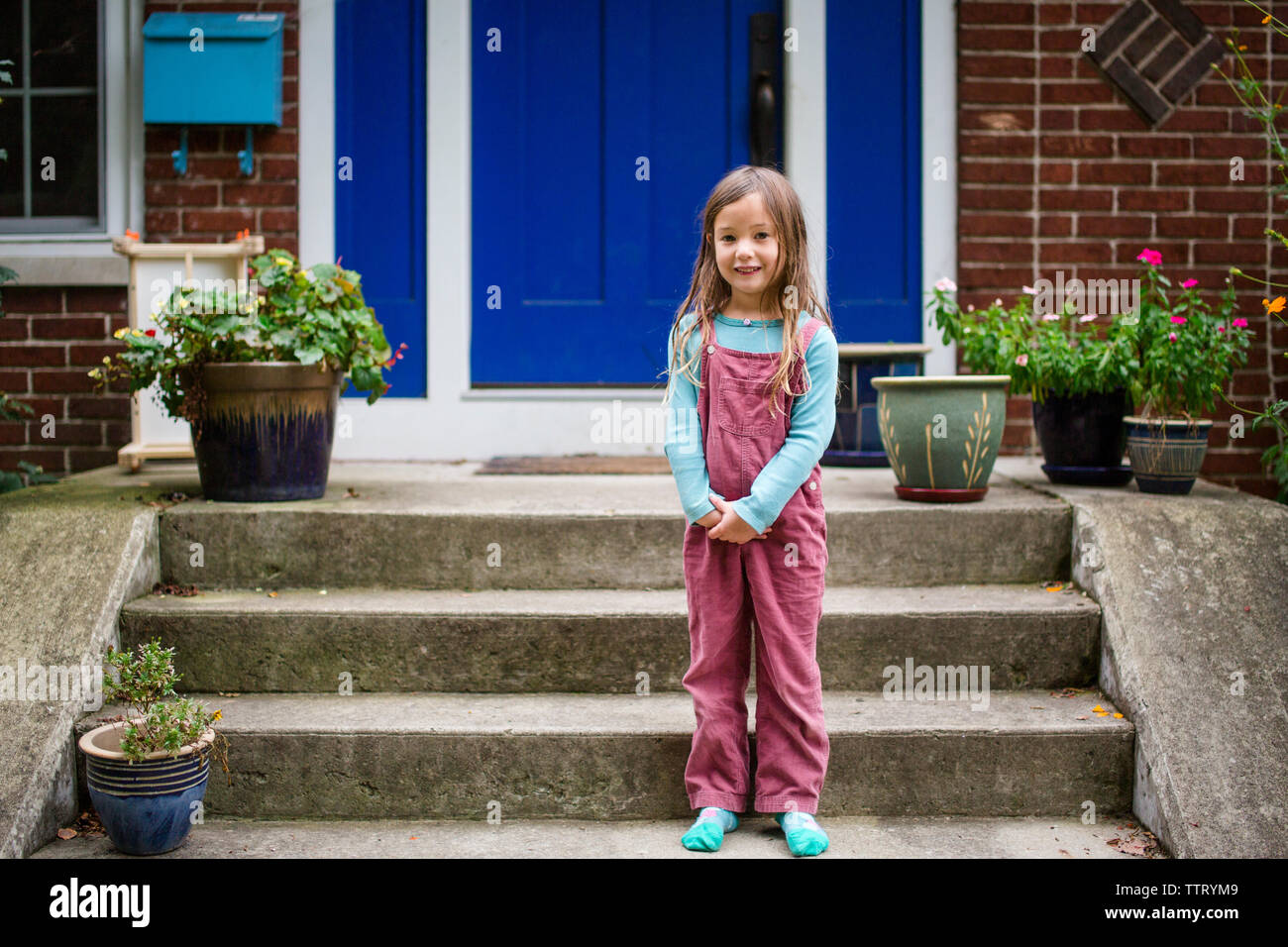Portrait of a cute girl standing on her front stoop Stock Photo - Alamy