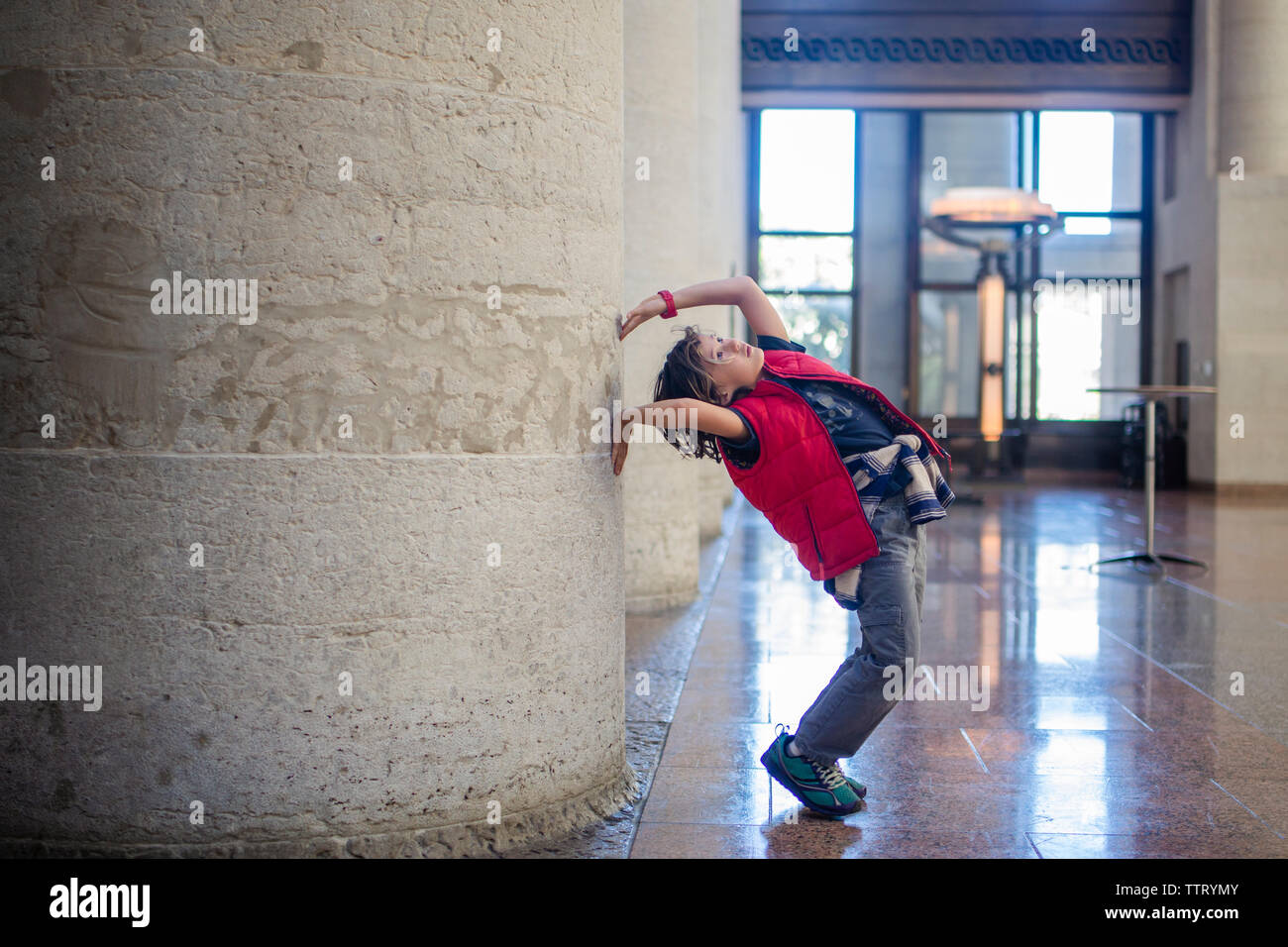 A boy arches back against a column in a museum Stock Photo - Alamy