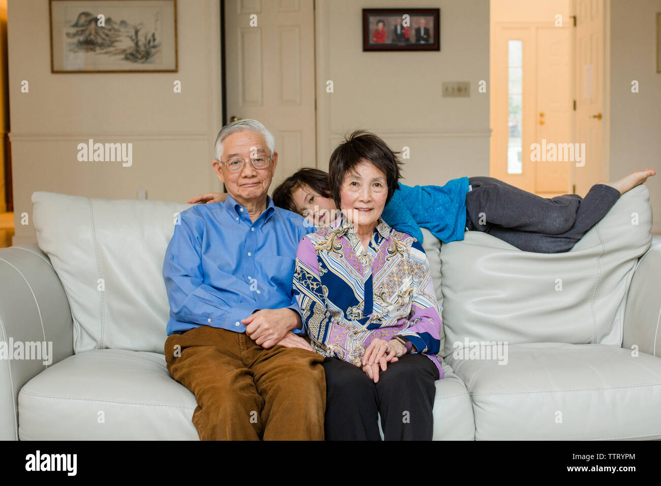 portrait Multi Ethnic Asian grandparents and grandson on couch at home ...