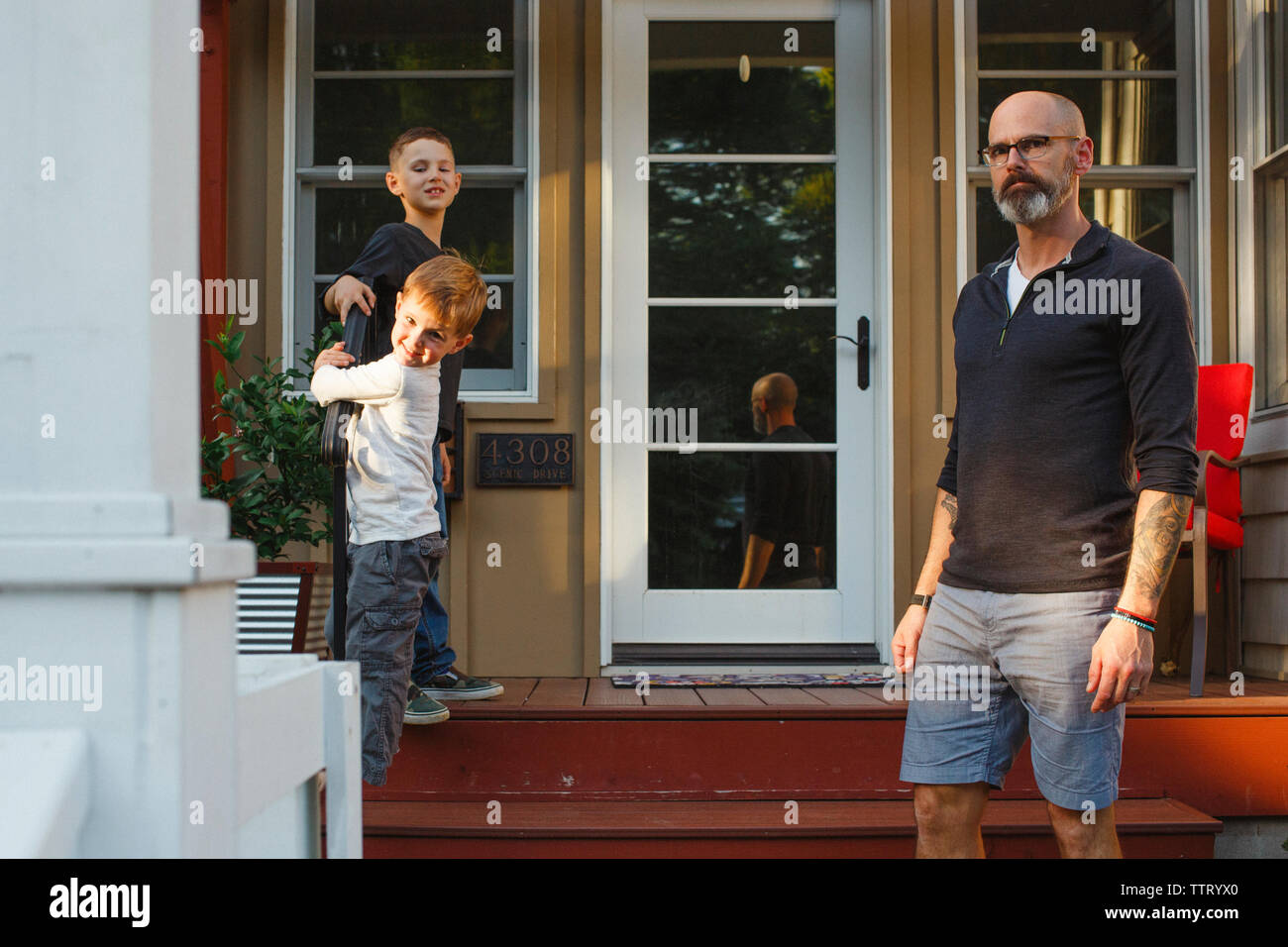 a father stands on his front stoop with his two small boys Stock Photo ...