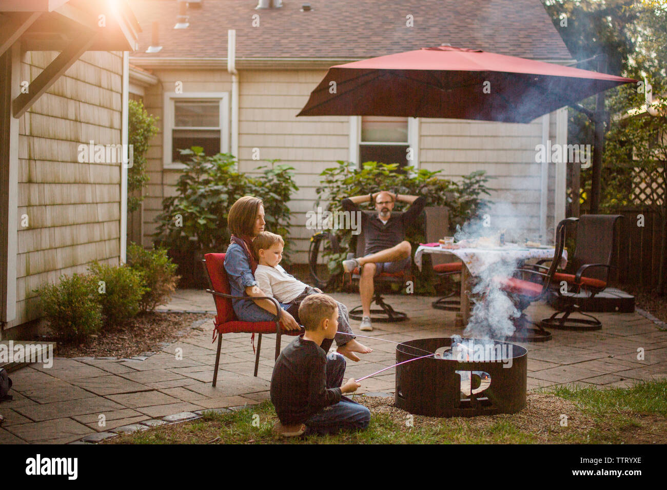 a family sitting together in backyard at sunset Stock Photo - Alamy