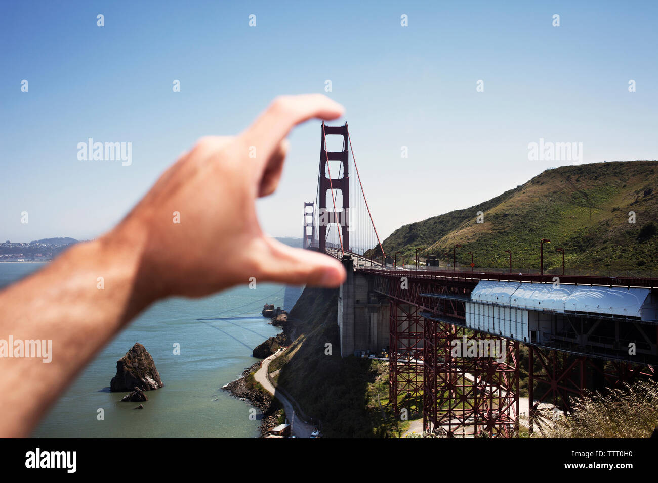 Optical illusion of man's hand holding Golden Gate Bridge against clear ...