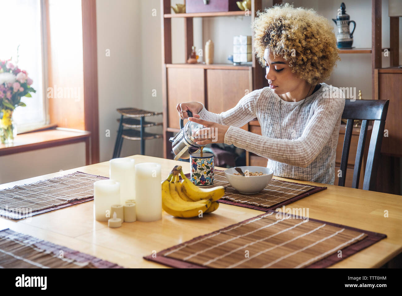 Woman pouring coffee in cup at table in house Stock Photo - Alamy