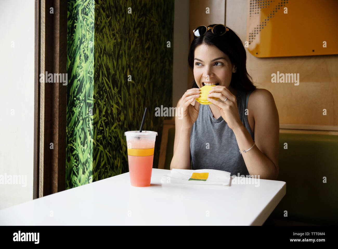 Beautiful woman eating macaroon and having juice at restaurant Stock ...