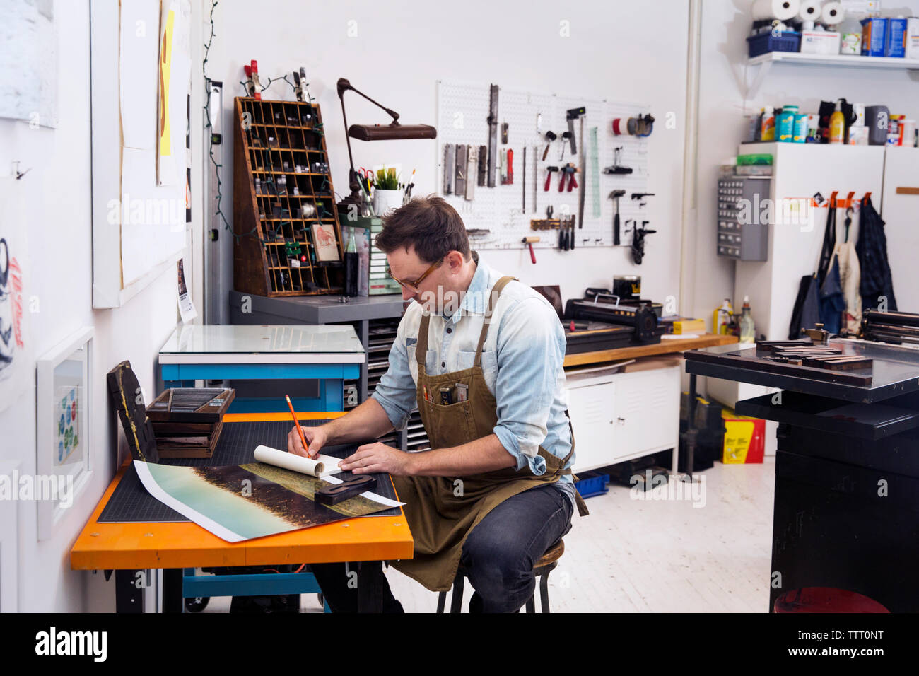 Serious man writing on paper while sitting in printing press Stock ...