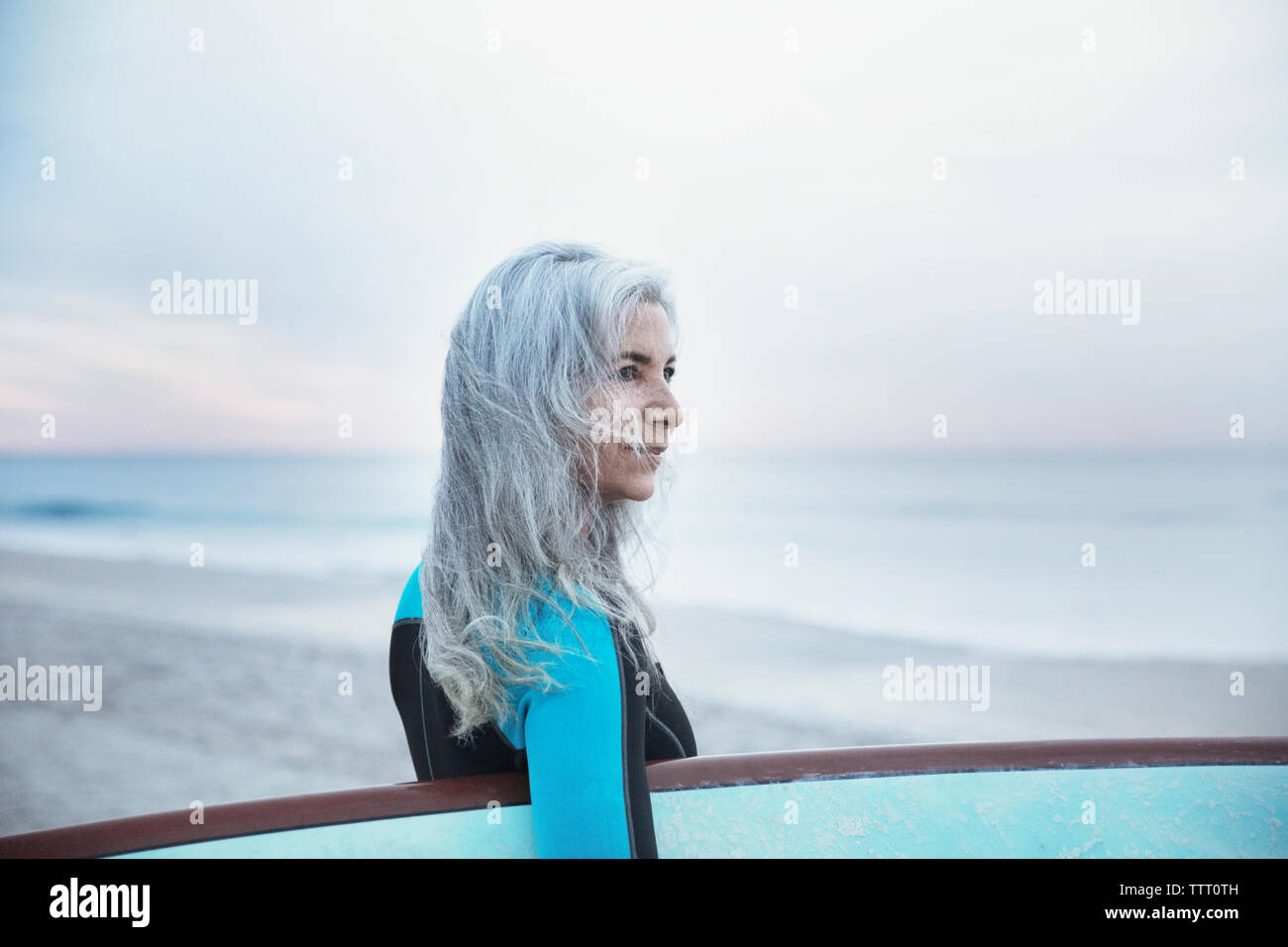 Side view thoughtful female surfer carrying surfboard at Delray Beach ...