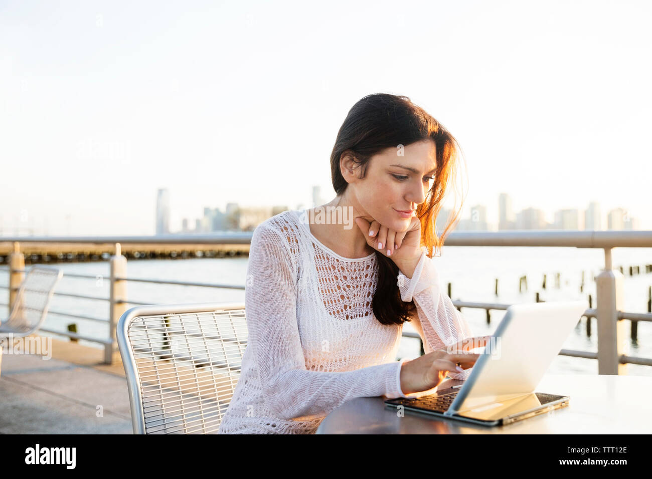 Woman using tablet computer at cafe on promenade during sunset Stock ...