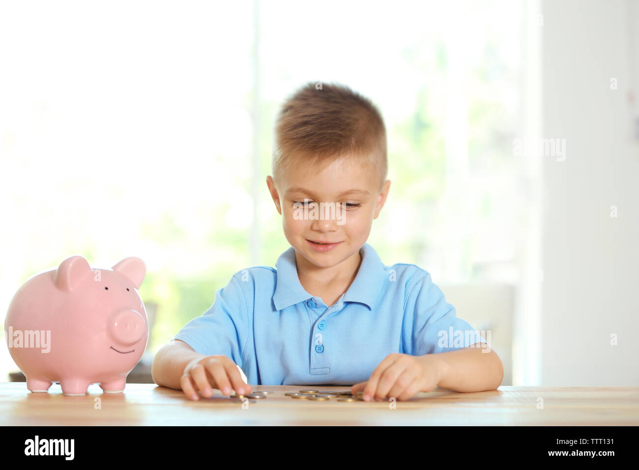 Savings concept. Little boy counting coins at table with piggy bank ...