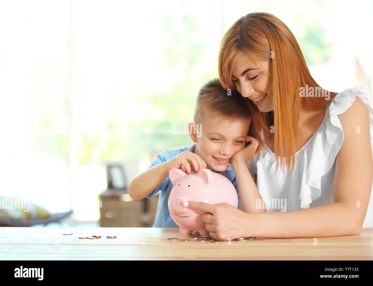 Savings concept. Mother and little boy putting coins into piggy bank ...