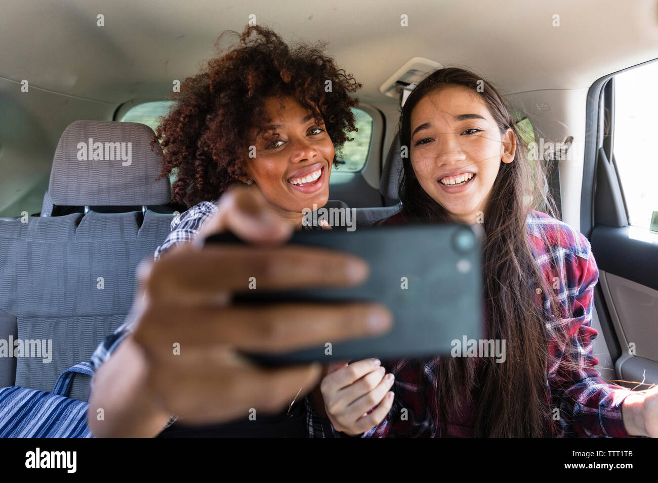 Happy friends talking selfie while traveling in car Stock Photo - Alamy