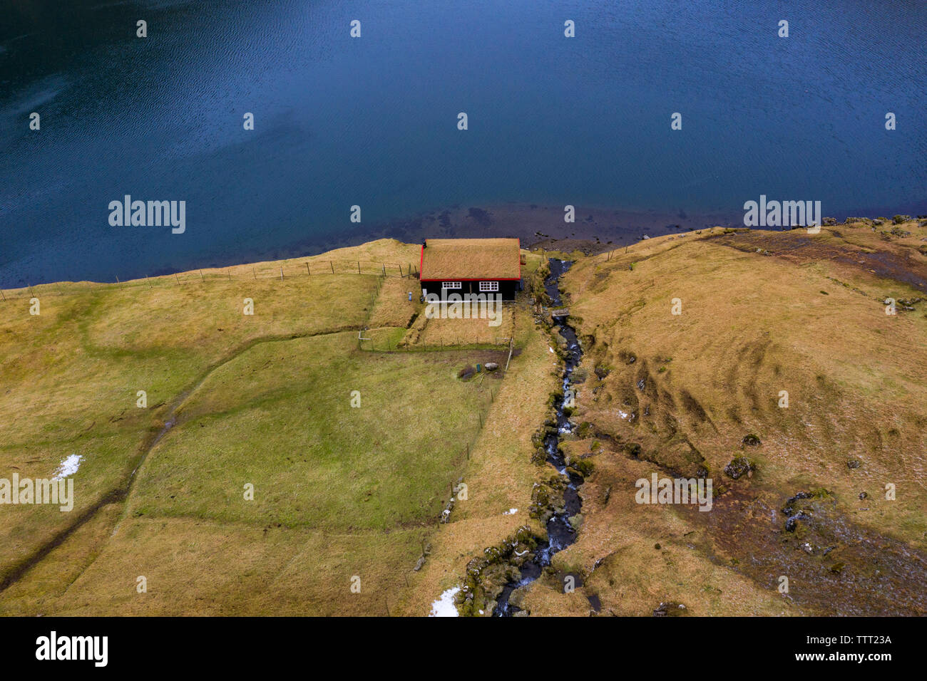 Elevated view of isolated house with grass roof in front of lagoon ...