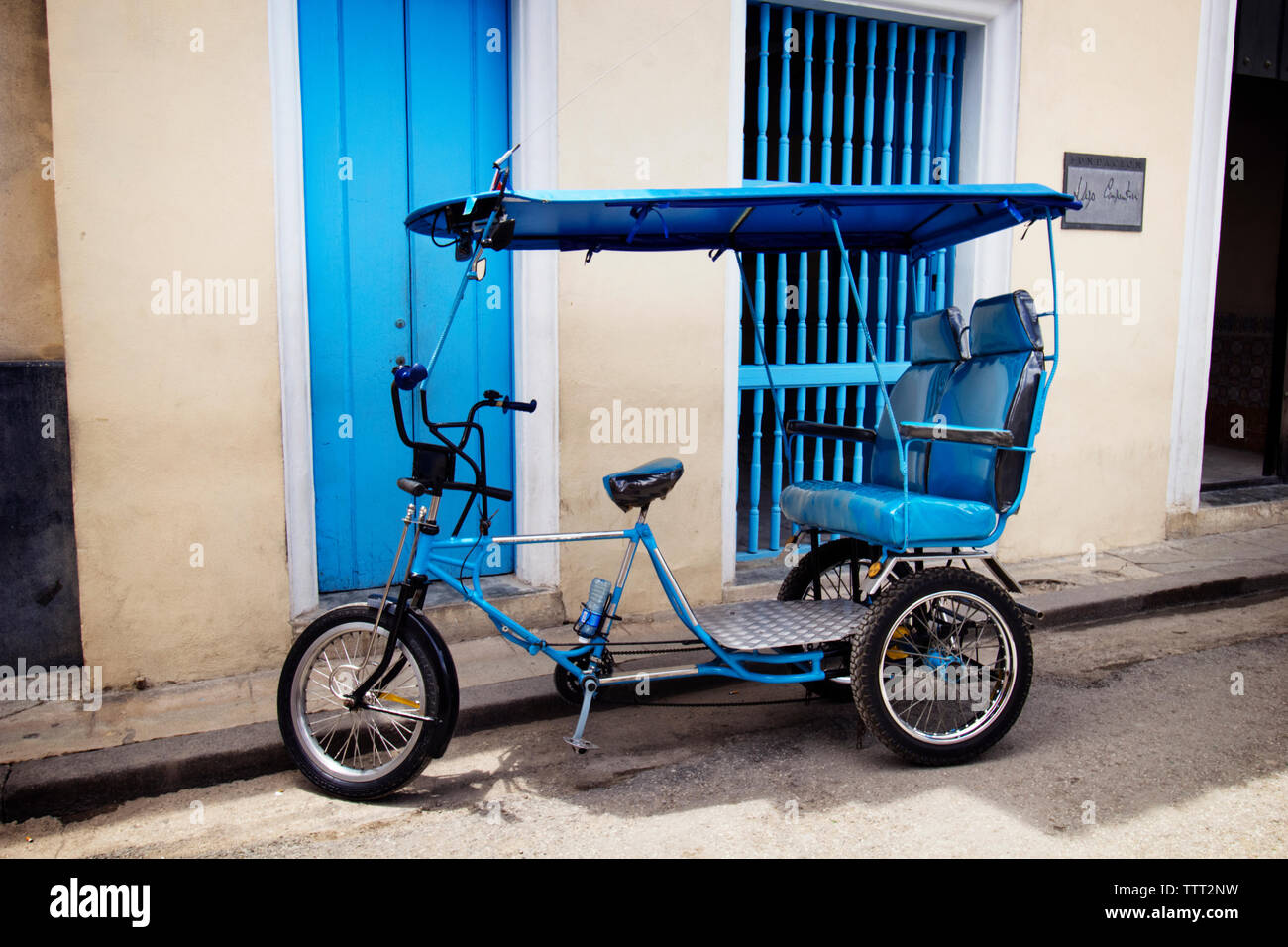 Rickshaw parked on street by building Stock Photo - Alamy