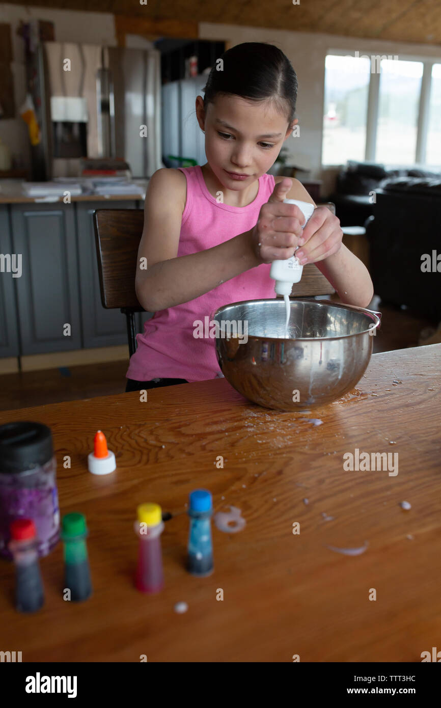 tween girl putting glue in a bowl to make slime Stock Photo - Alamy