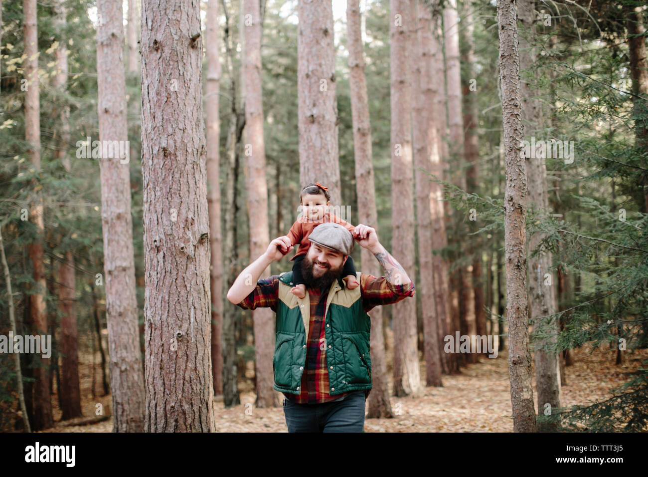 Happy father carrying daughter on shoulders while walking in forest ...