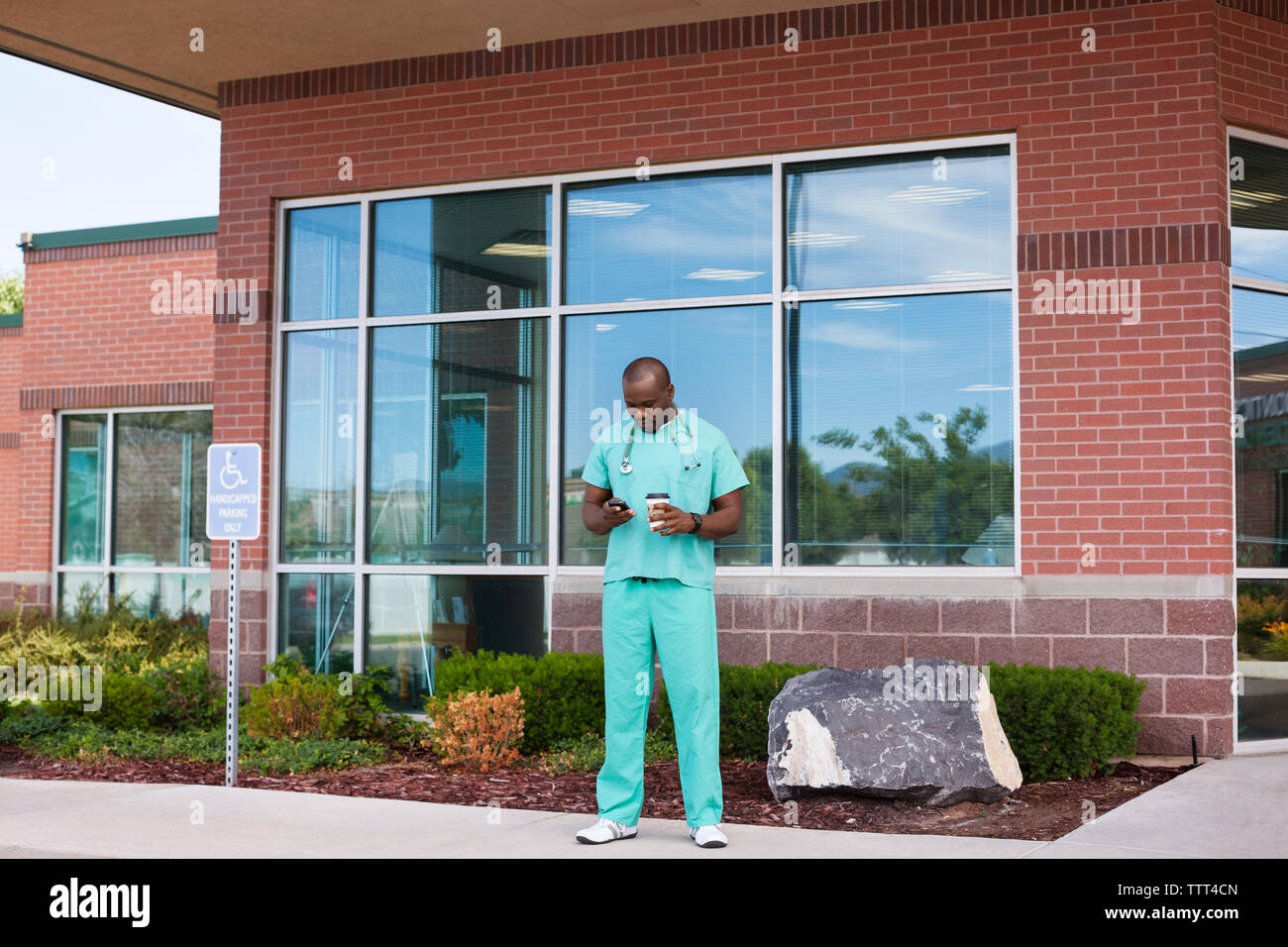 Doctor using phone while standing outside hospital Stock Photo - Alamy