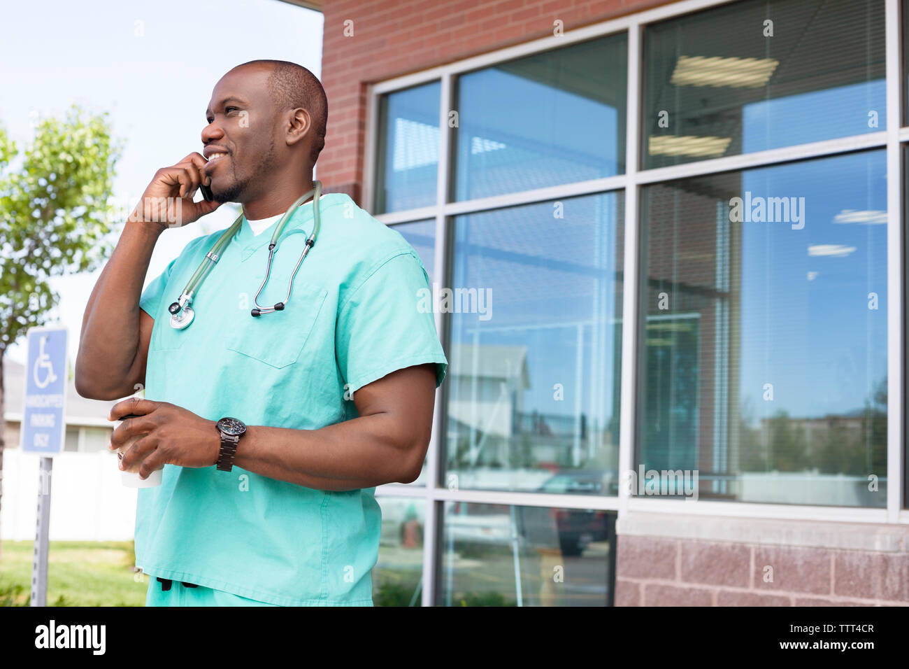 Doctor talking on mobile phone while standing outside hospital Stock ...