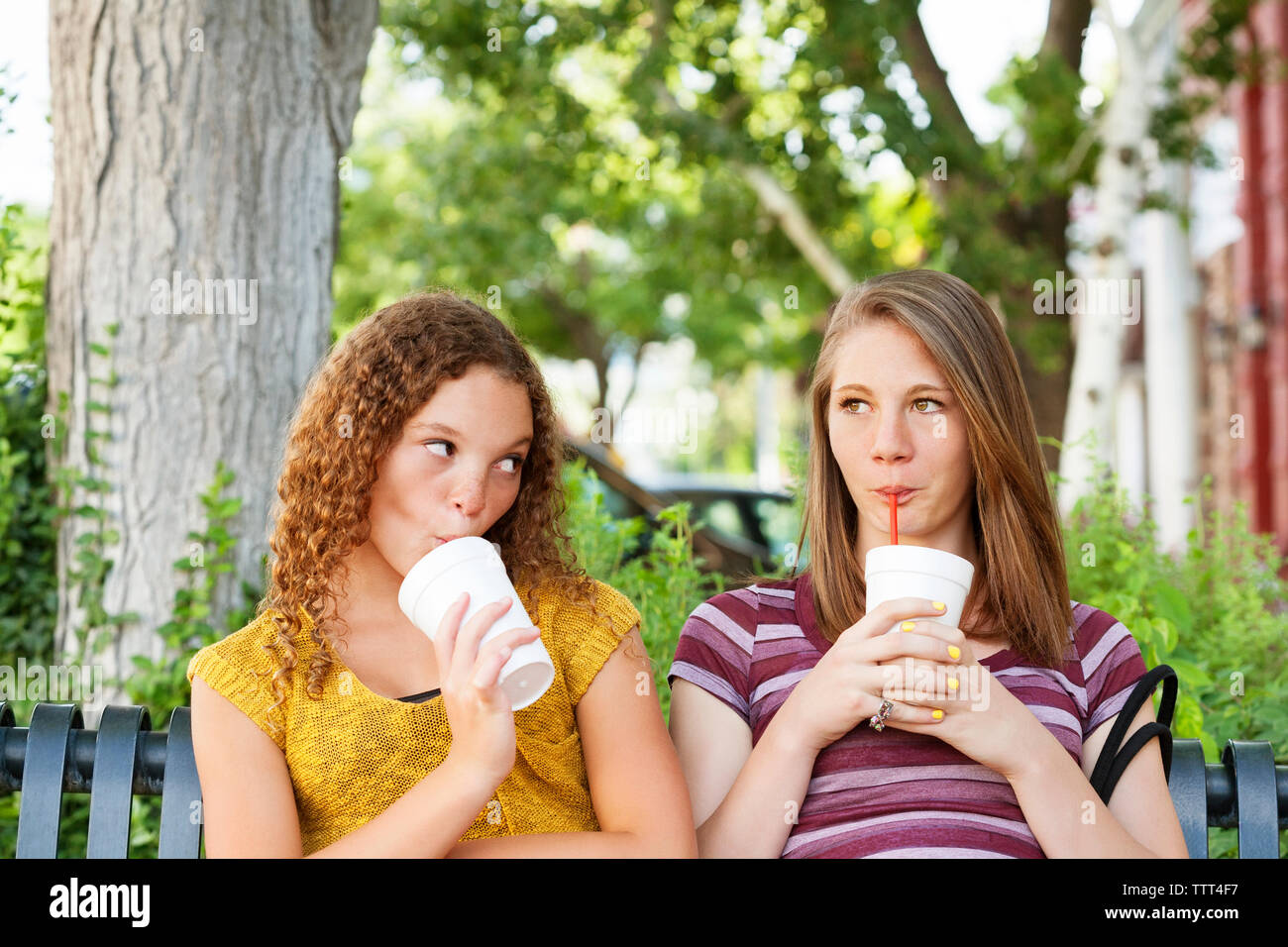 Two girls sitting on park bench hi-res stock photography and images - Alamy