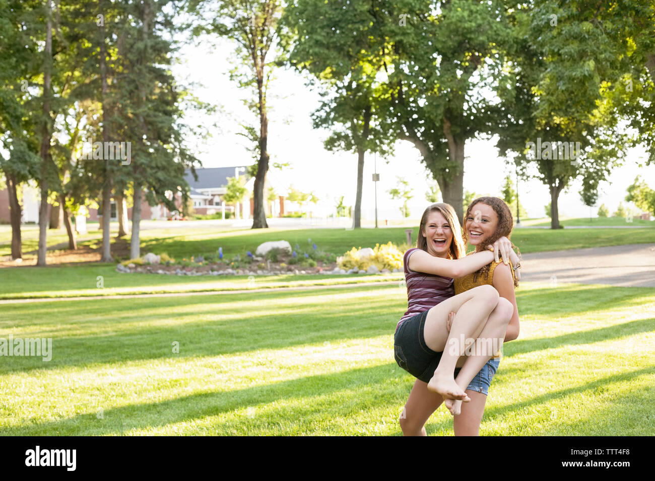 Portrait of teenage girl carrying friend at park Stock Photo - Alamy
