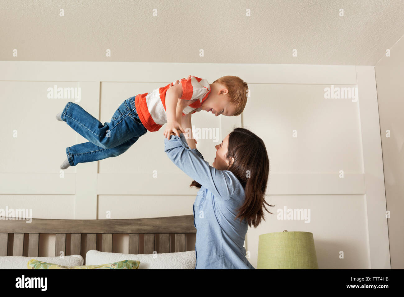 Mother lifting boy in bedroom at home Stock Photo - Alamy