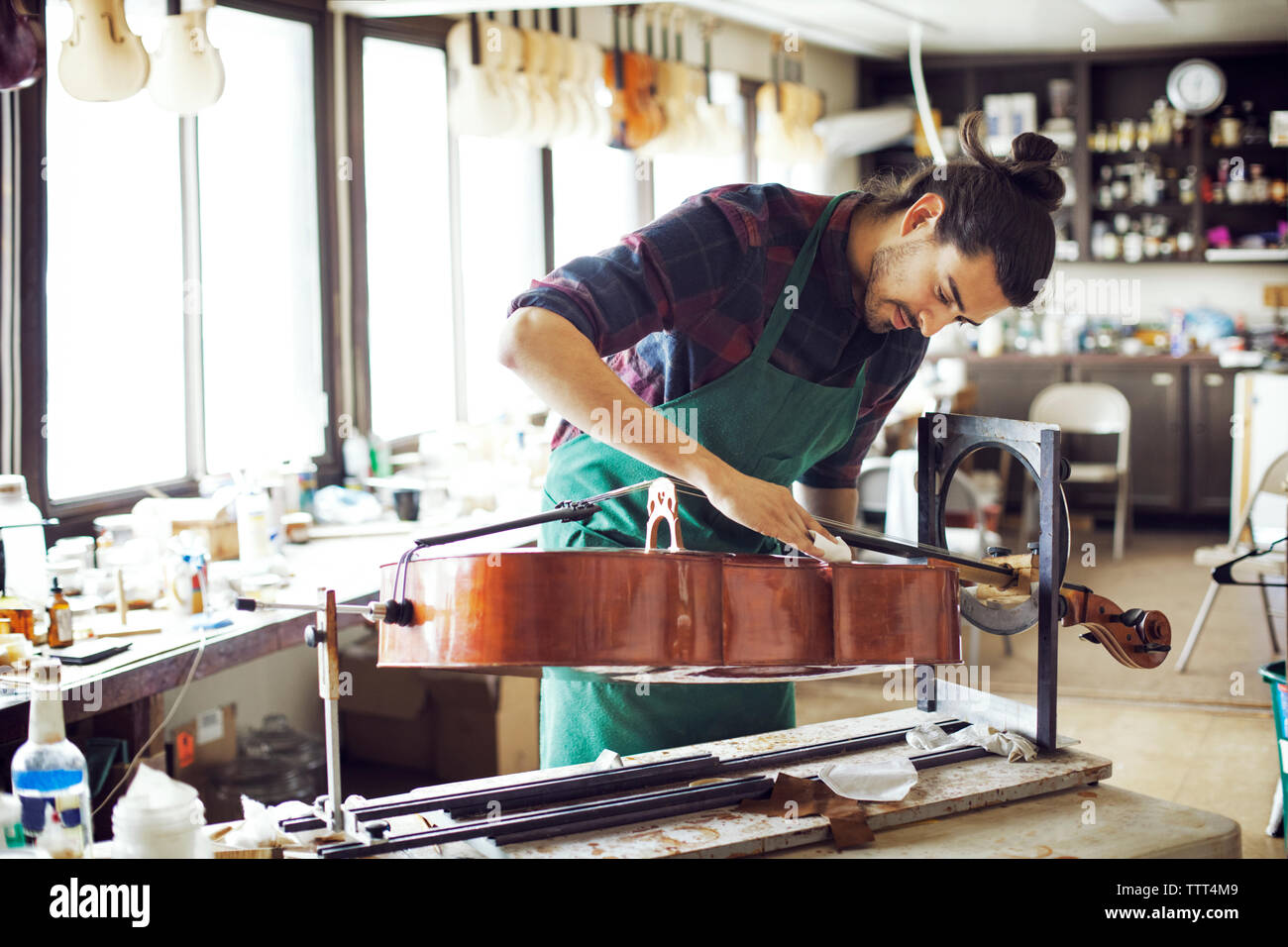 Man cleaning violin on stand while working in workshop Stock Photo - Alamy
