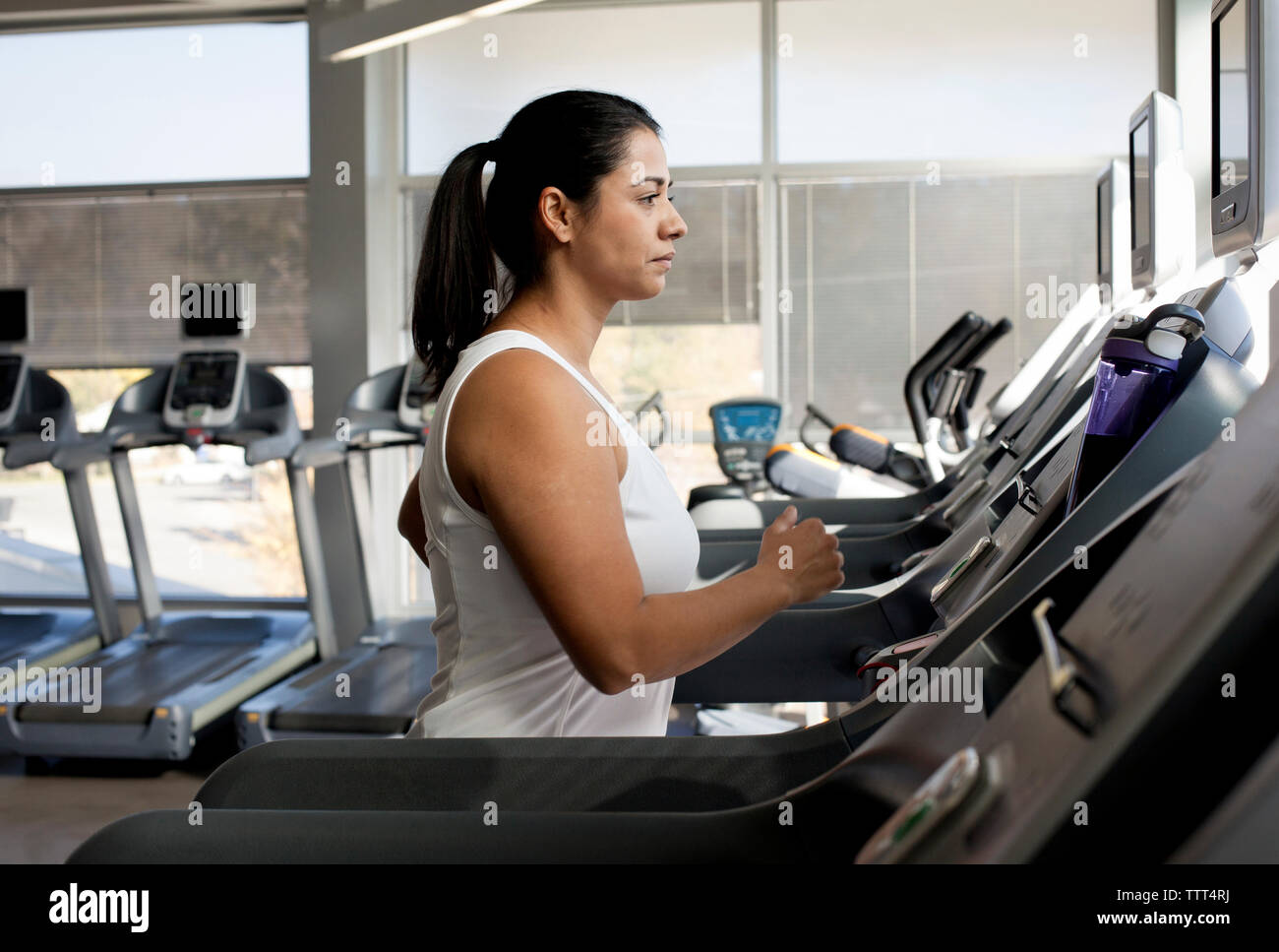 Side view of woman on treadmill in gym Stock Photo - Alamy