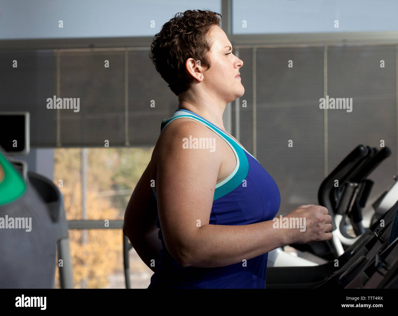 Side view of curvy woman exercising on treadmill Stock Photo - Alamy